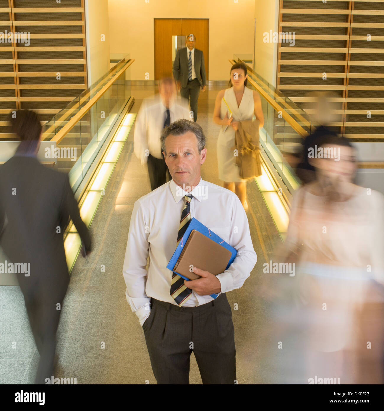 Businessman standing in busy office corridor Stock Photo - Alamy
