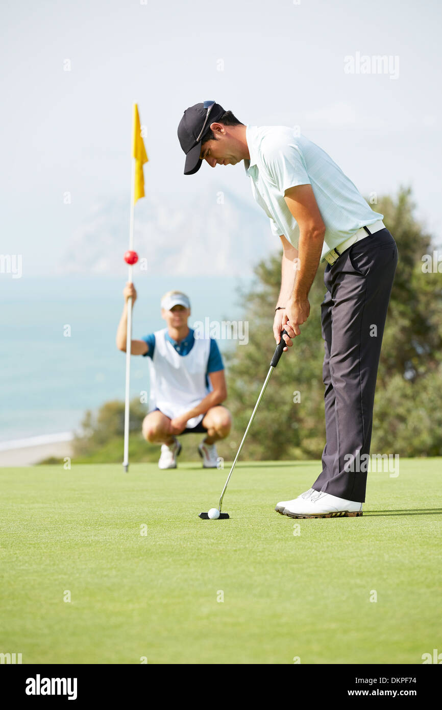 Caddy watching man putt Stock Photo - Alamy