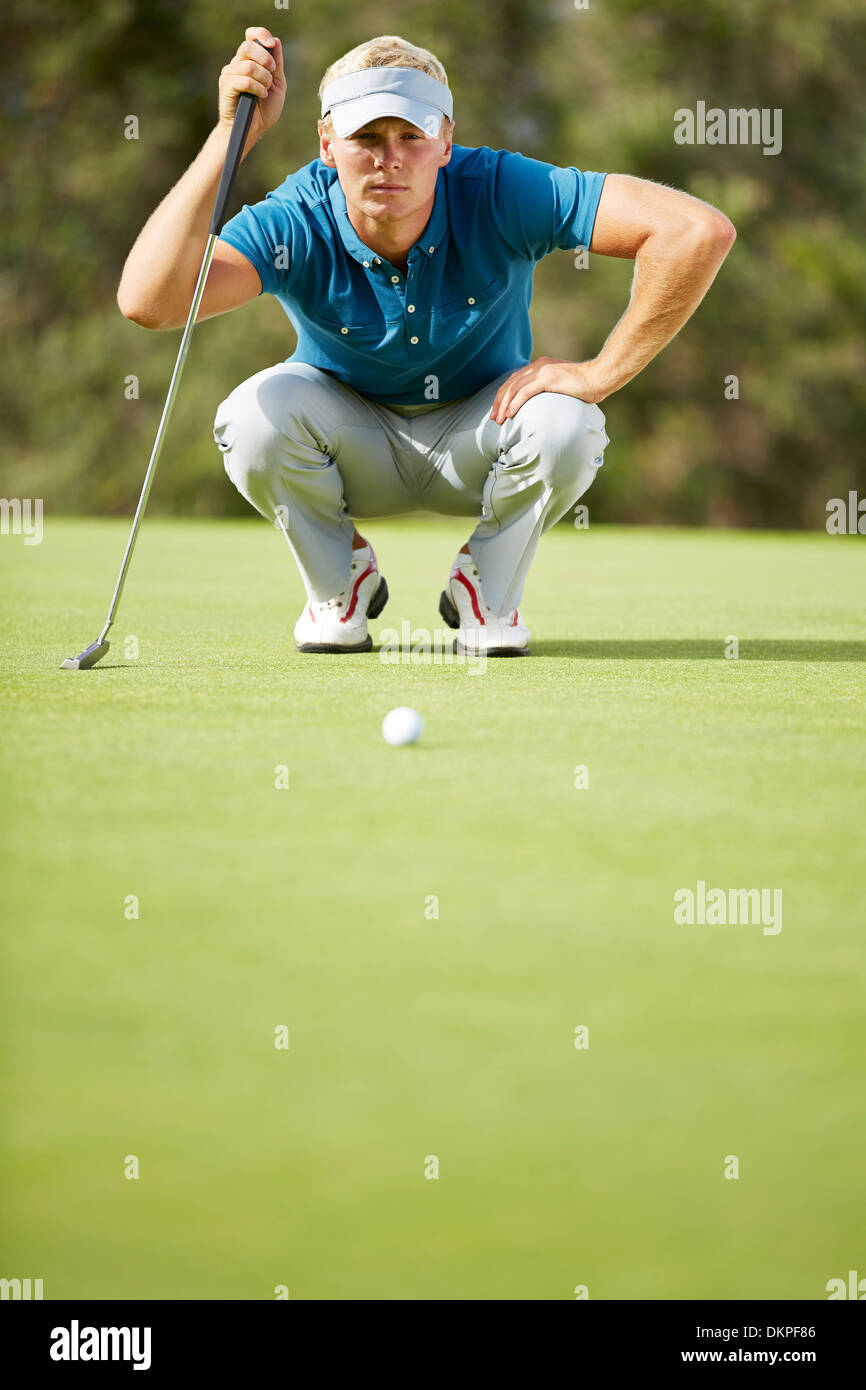 Man preparing to putt on golf course Stock Photo - Alamy