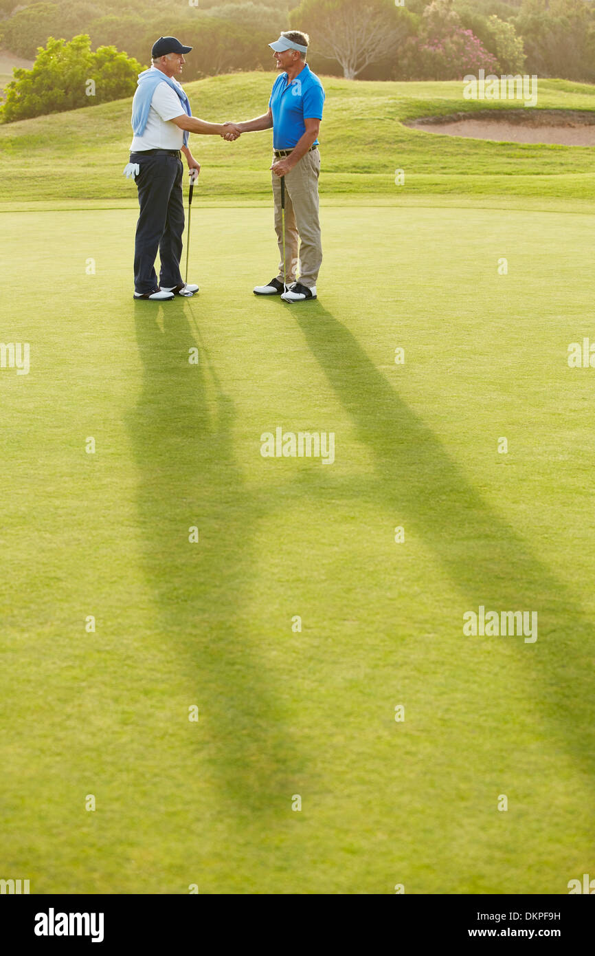 Senior men shaking hands on golf course Stock Photo - Alamy