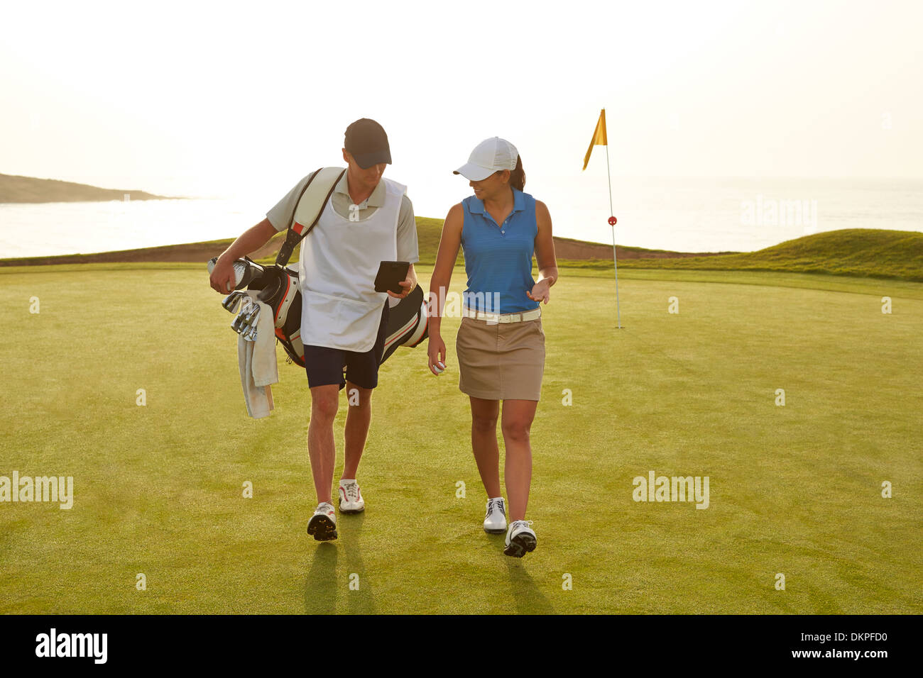 Golfer and caddy walking on golf course Stock Photo - Alamy