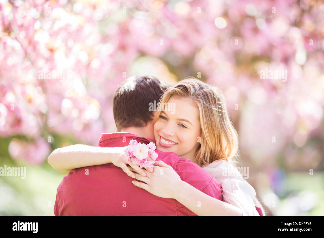Couple hugging under tree with pink blossoms Stock Photo - Alamy