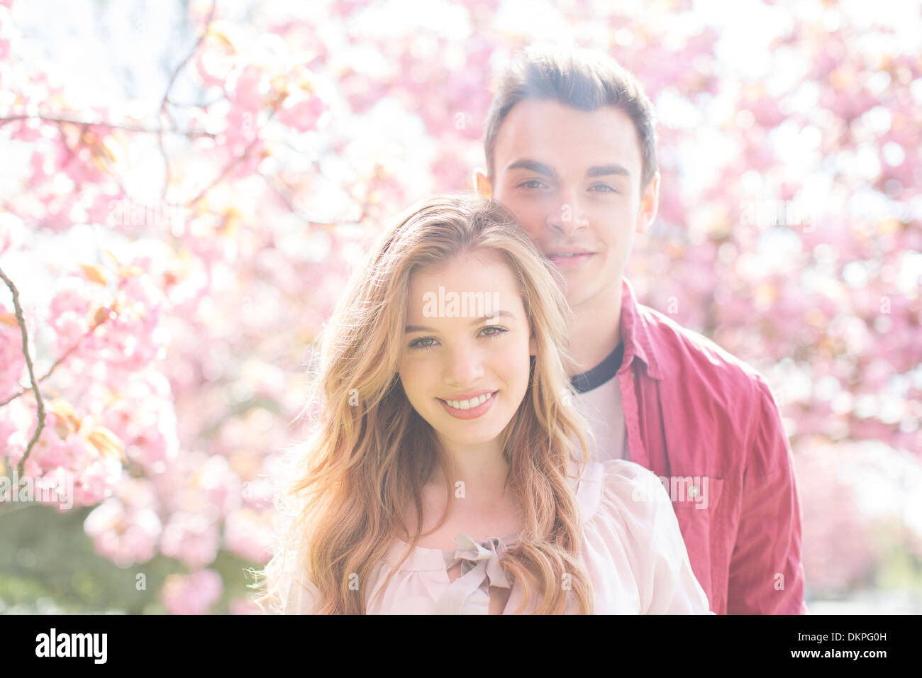 Couple hugging under tree with pink blossoms Stock Photo - Alamy