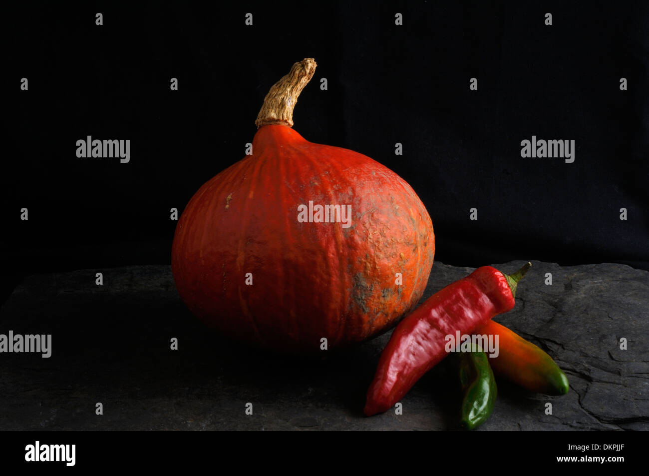 Still life of squash and chilli peppers on slate background Stock Photo ...