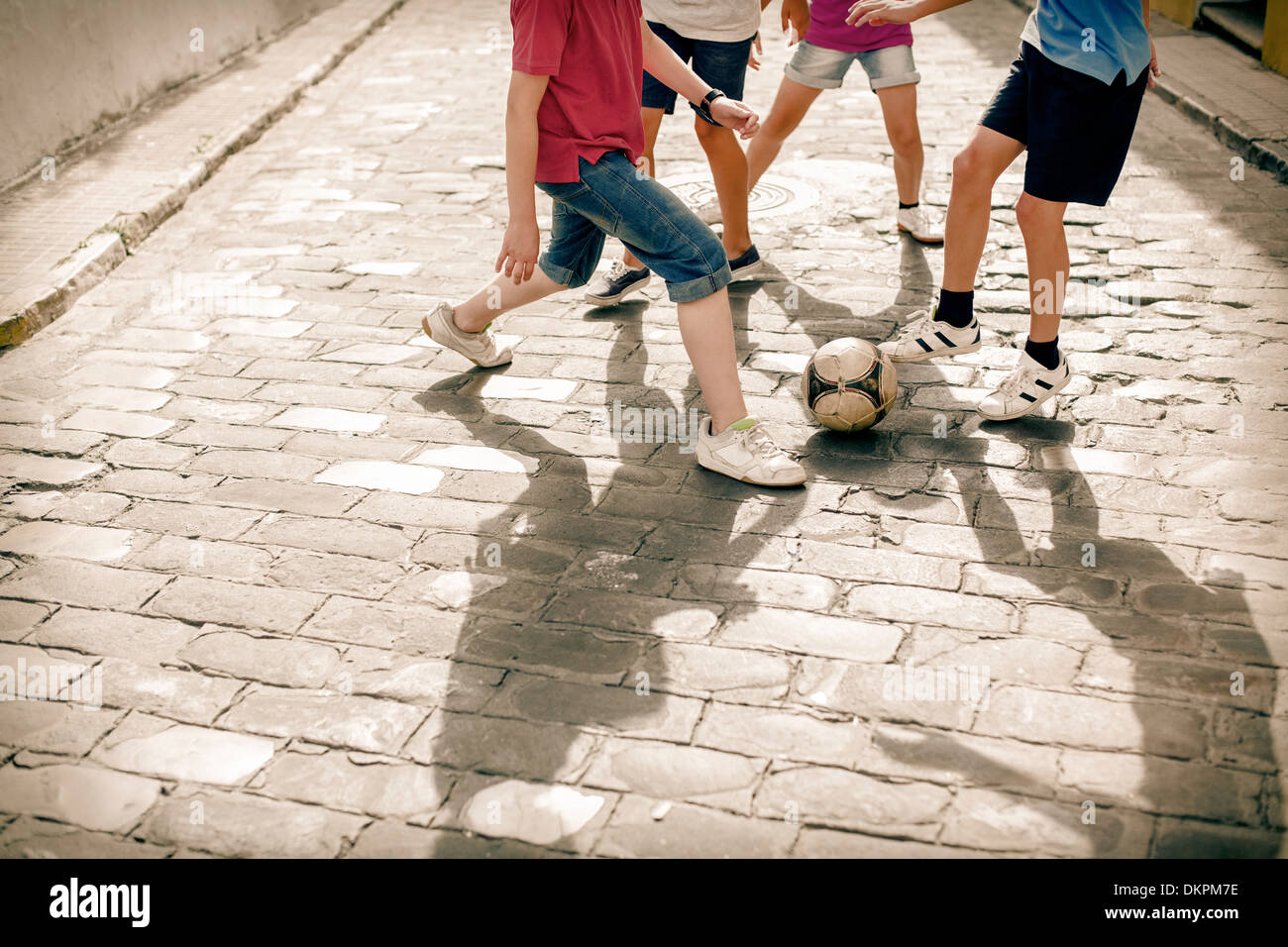Children playing with soccer ball on cobblestone street Stock Photo - Alamy