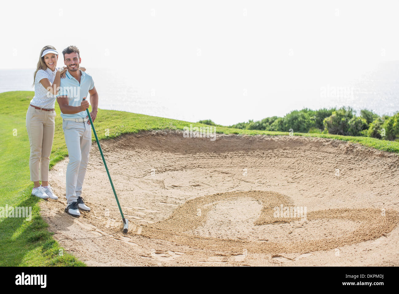 Couple drawing heart-shape in sand trap on golf course Stock Photo - Alamy