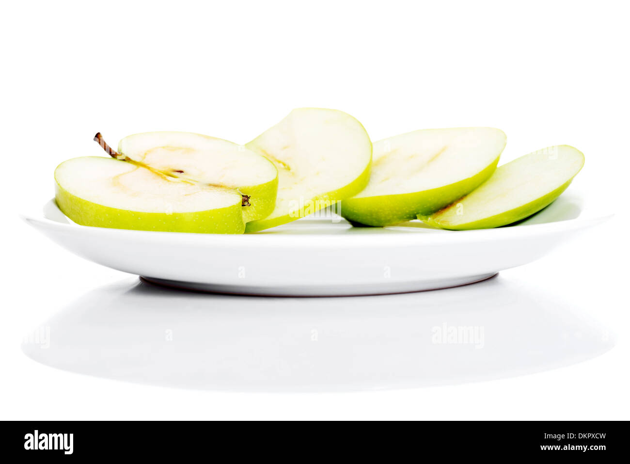 Green apples divided into two half lying in a white bowl. isolated on ...