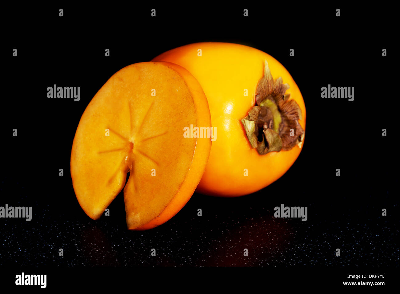 Kaki fruit with one sliced kaki piece. Over black background Stock ...