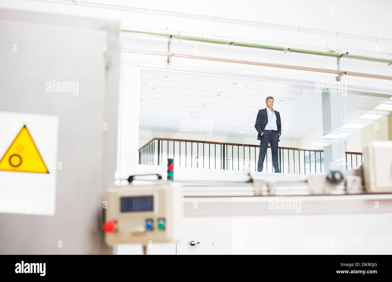 Businessman looking out observation window in factory Stock Photo - Alamy