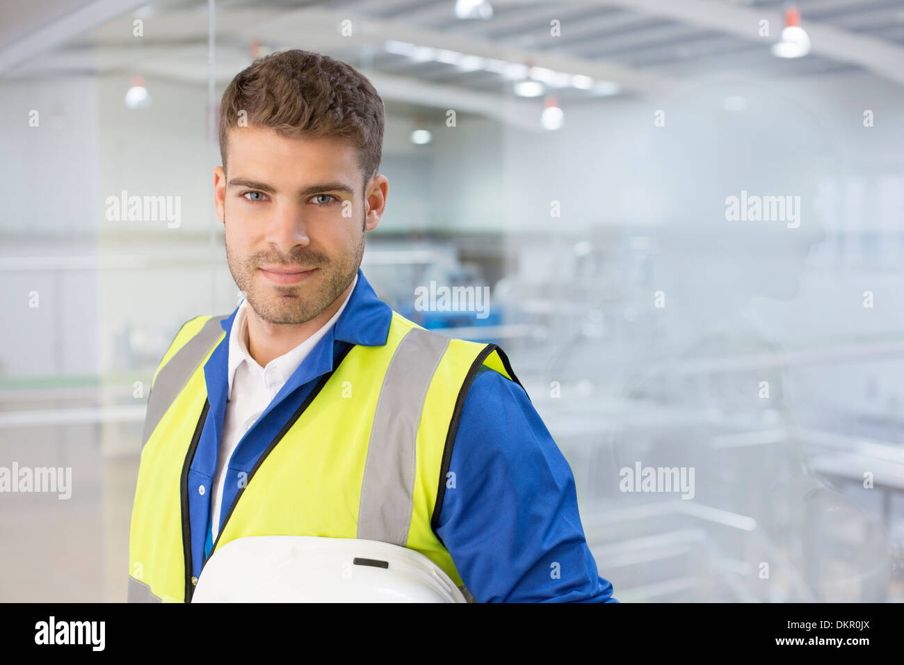 Worker smiling by window in factory Stock Photo - Alamy