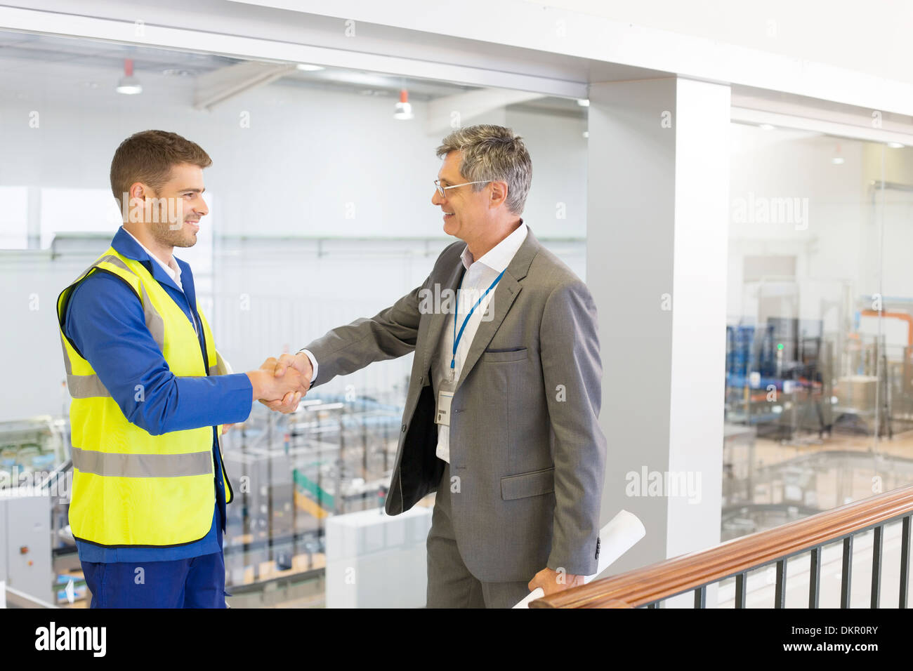 Supervisor and worker shaking hands in factory Stock Photo - Alamy