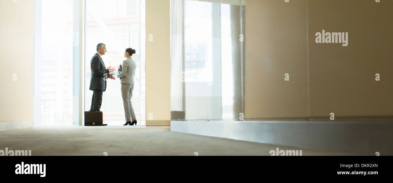 Business people talking at office window Stock Photo - Alamy