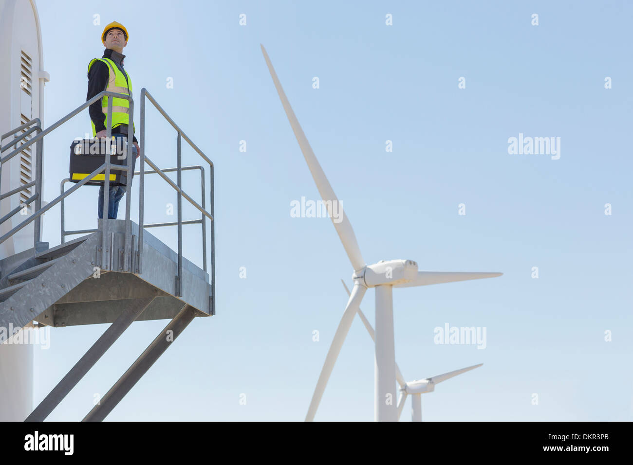 Worker standing on wind turbine in rural landscape Stock Photo - Alamy