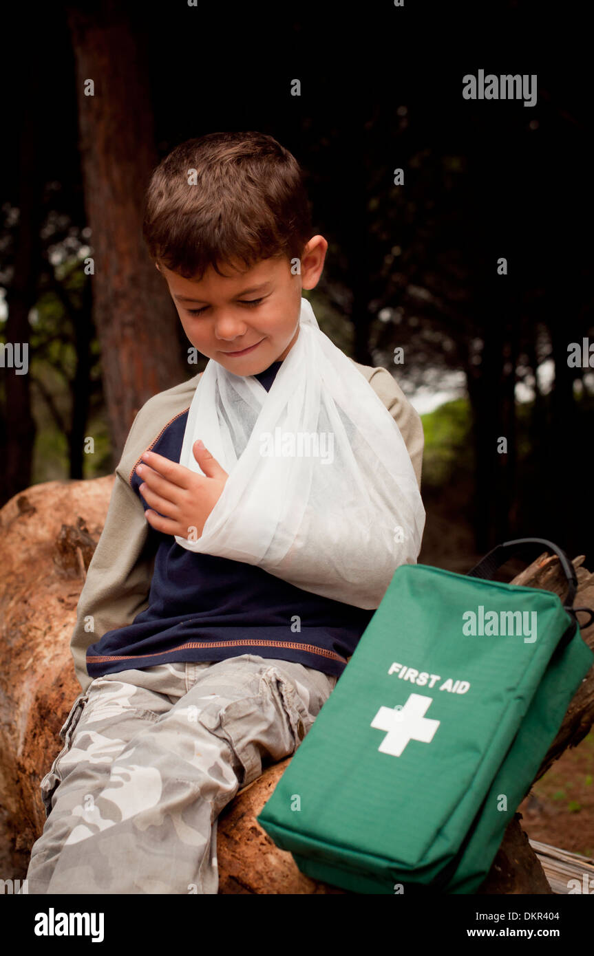 First Aid treatment given to a young boy in the forest, showing an arm ...