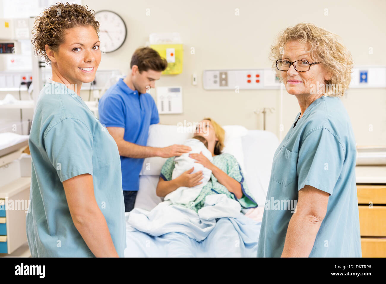 Successful Nurses Standing Against Couple With Baby In Backgroun Stock ...