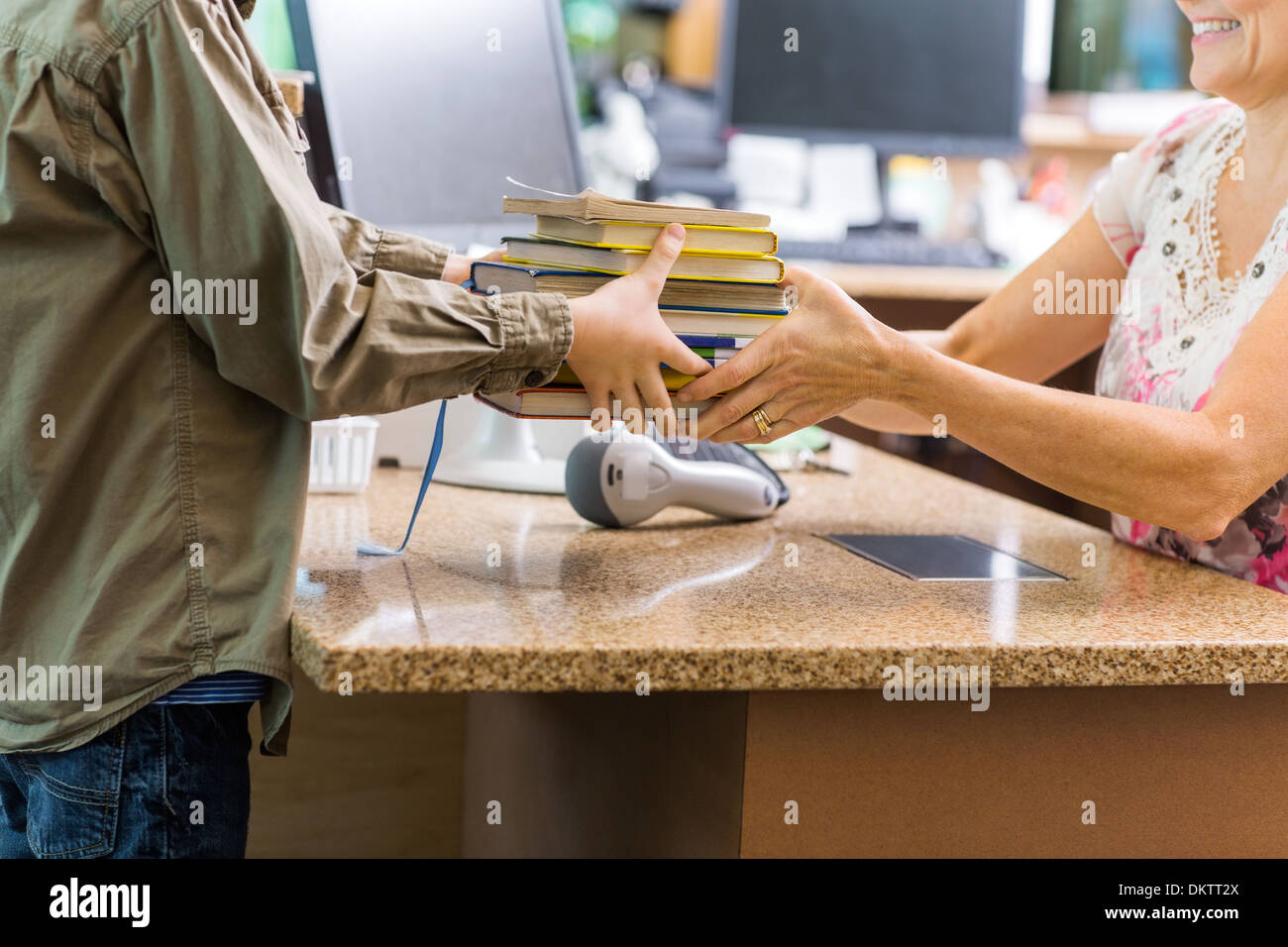 Boy Giving Books To Librarian At Library Counter Stock Photo: 63855314 ...