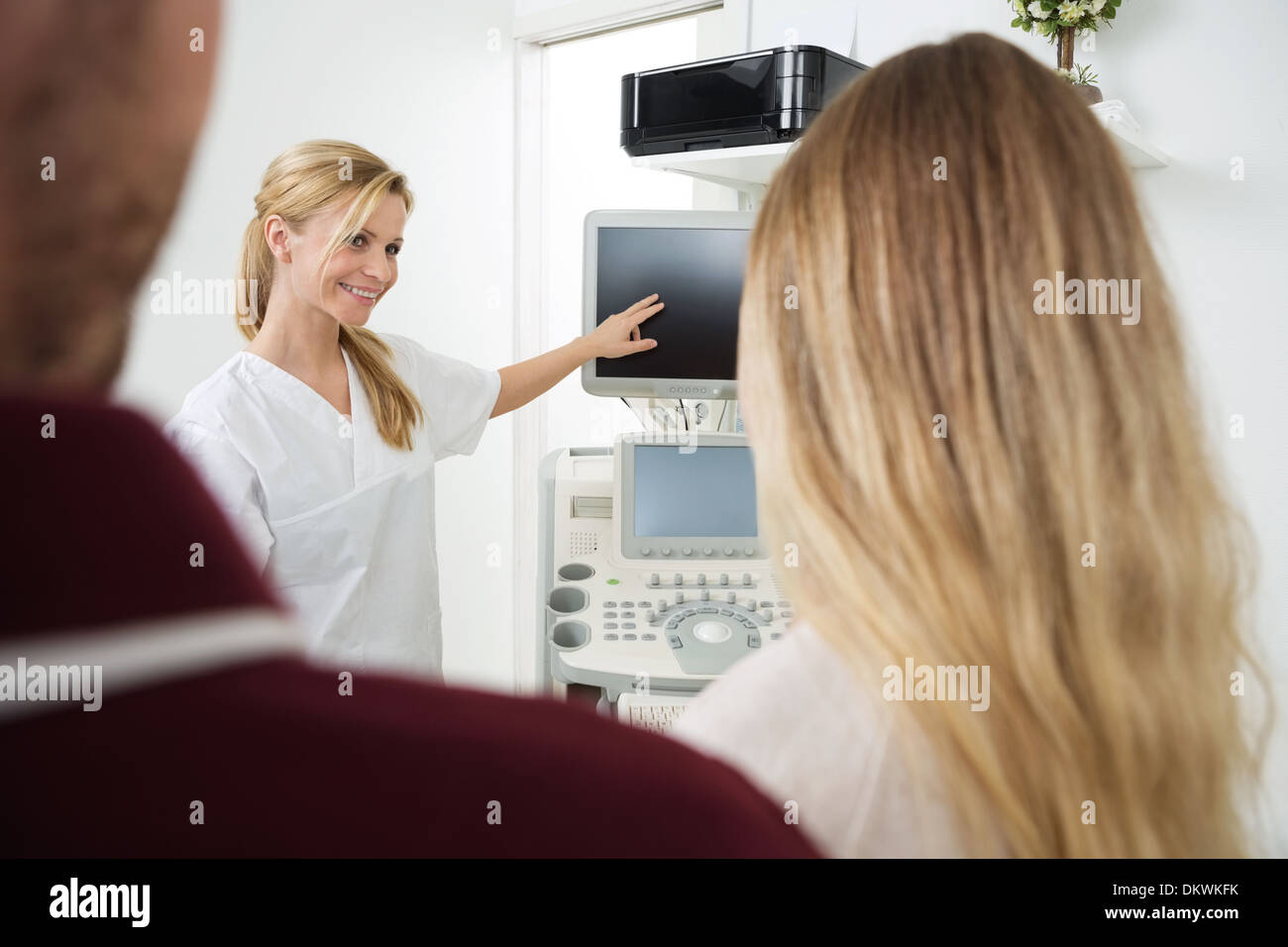 Gynecologist Showing Ultrasound Machine To Expectant Couple Stock Photo ...