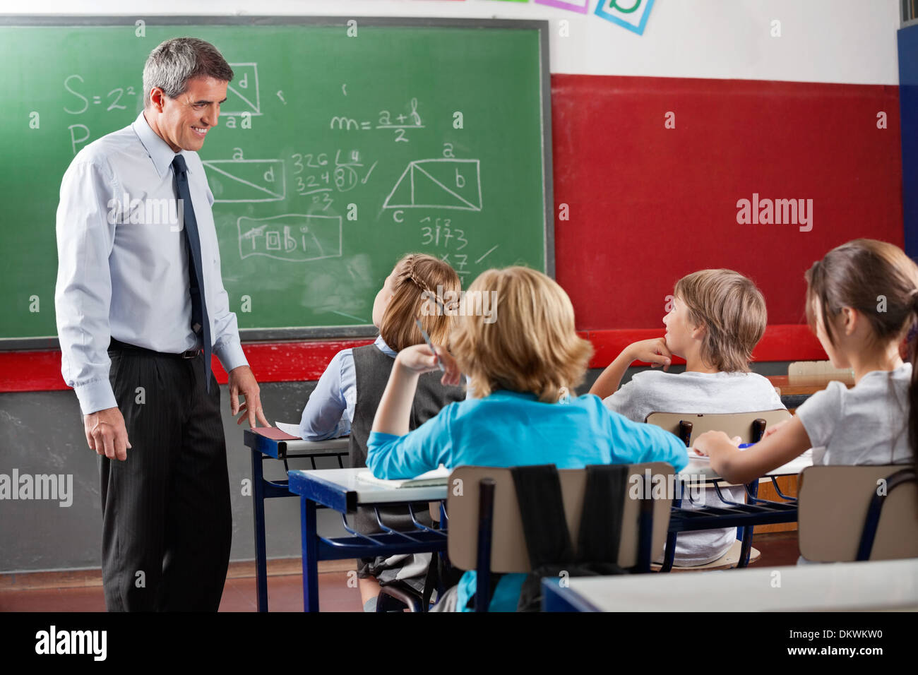 Teacher Looking At Students Sitting In Classroom Stock Photo - Alamy