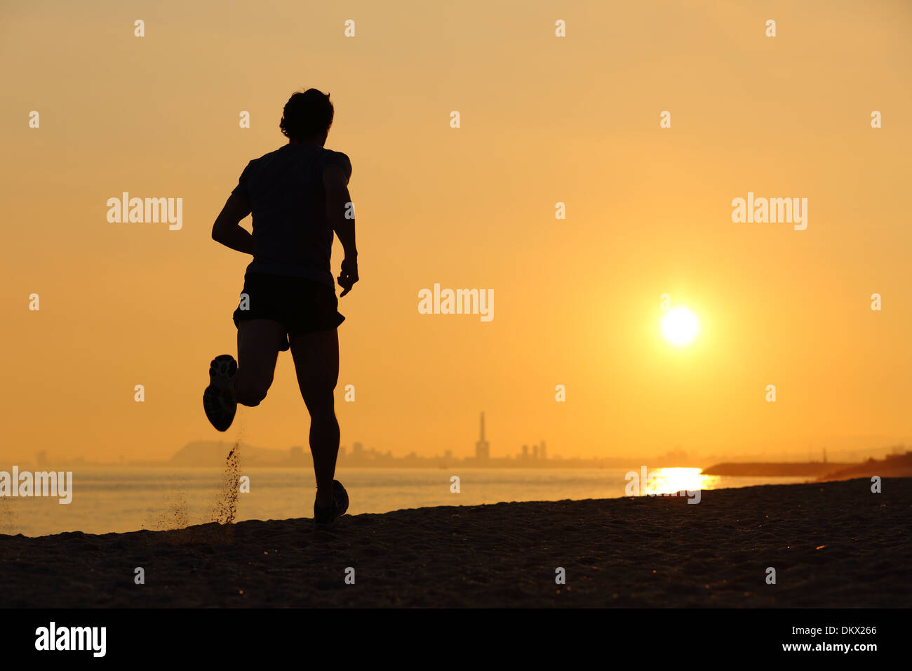 Backlight of a man running on the beach at sunset with the horizon in ...