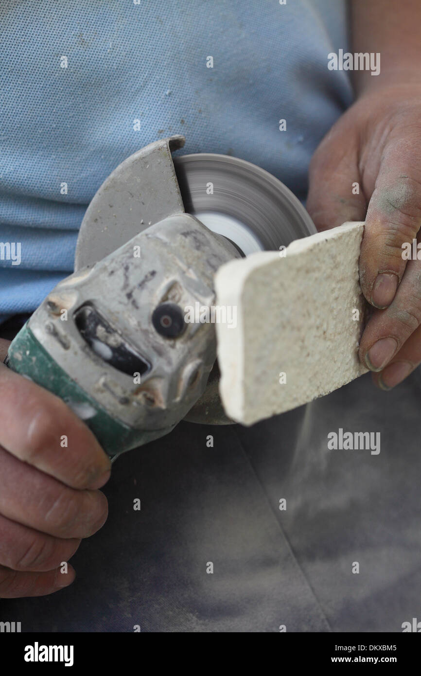 Renovation at home worker cuts tile with angle grinder electric tool ...