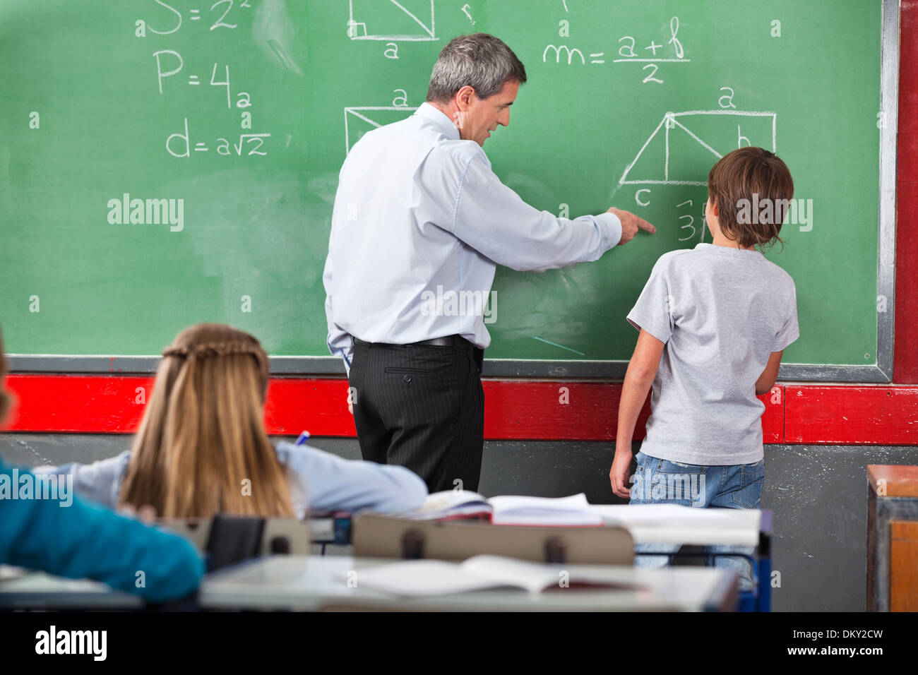 Teacher Assisting Schoolboy While Solving Mathematics Stock Photo - Alamy