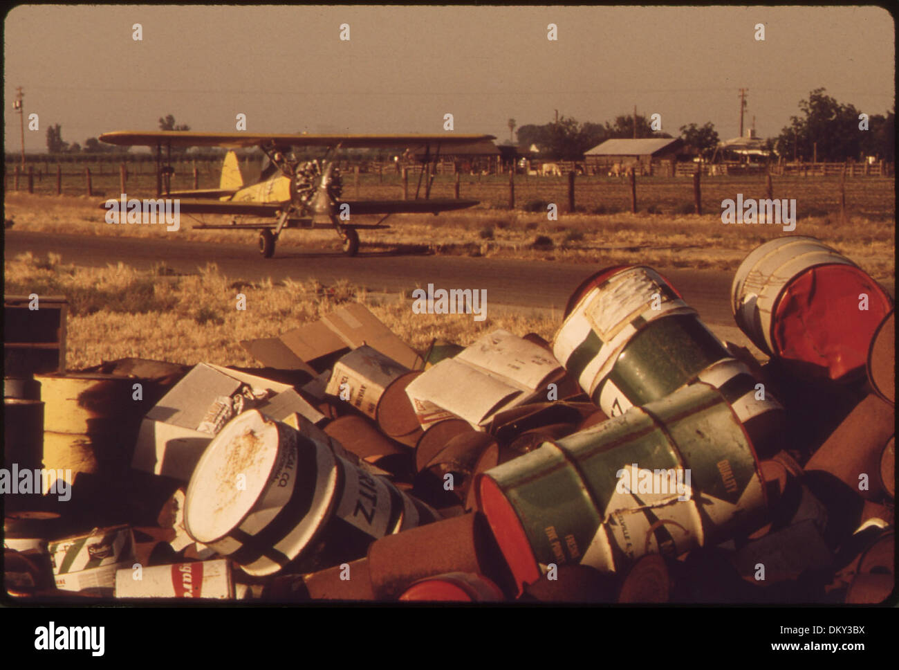 The image shows a collection of discarded pesticide cans, illustrating ...