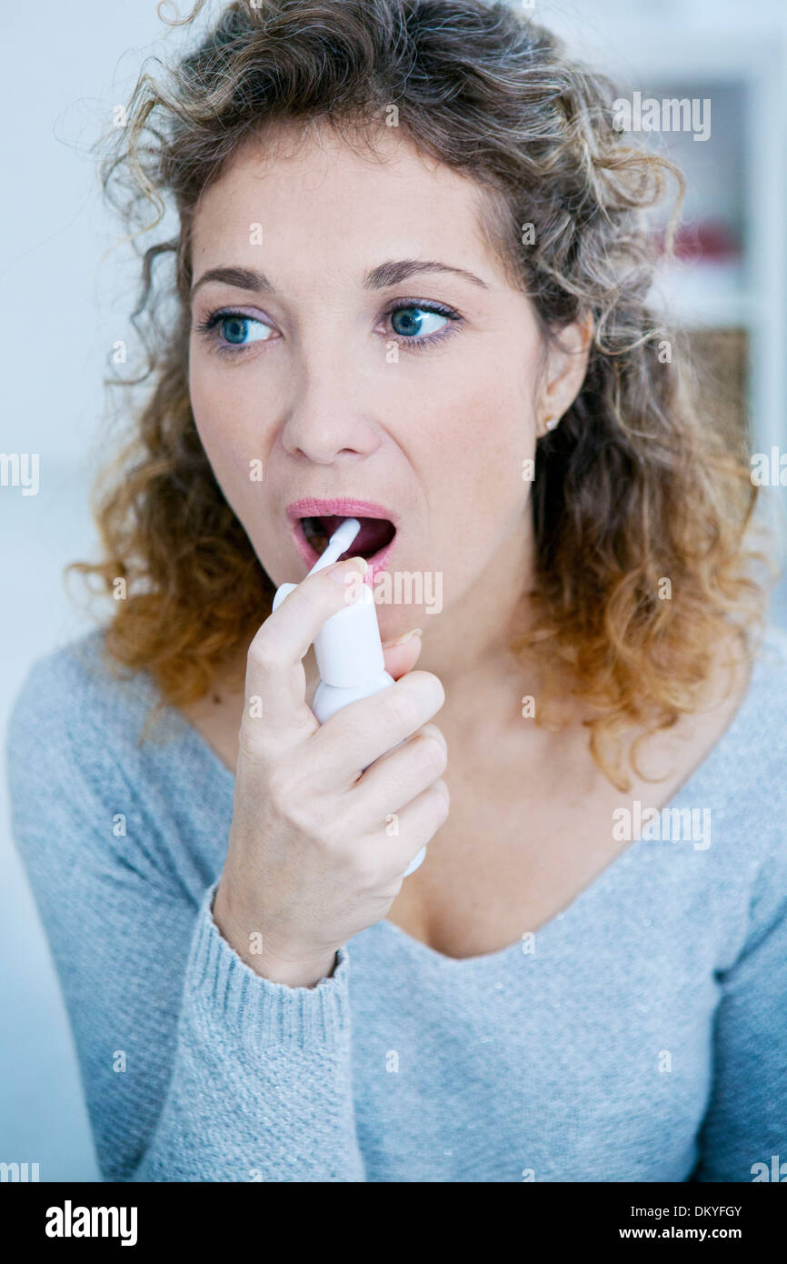 WOMAN USING SPRAY IN MOUTH Stock Photo - Alamy