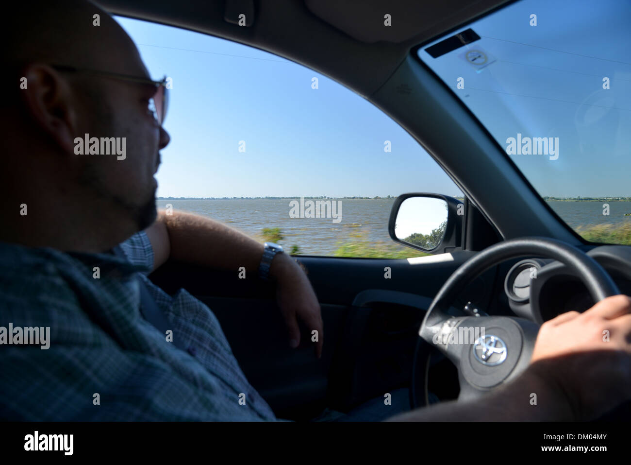 Happy car driver looks out the side window at a vast lake in Texas as ...