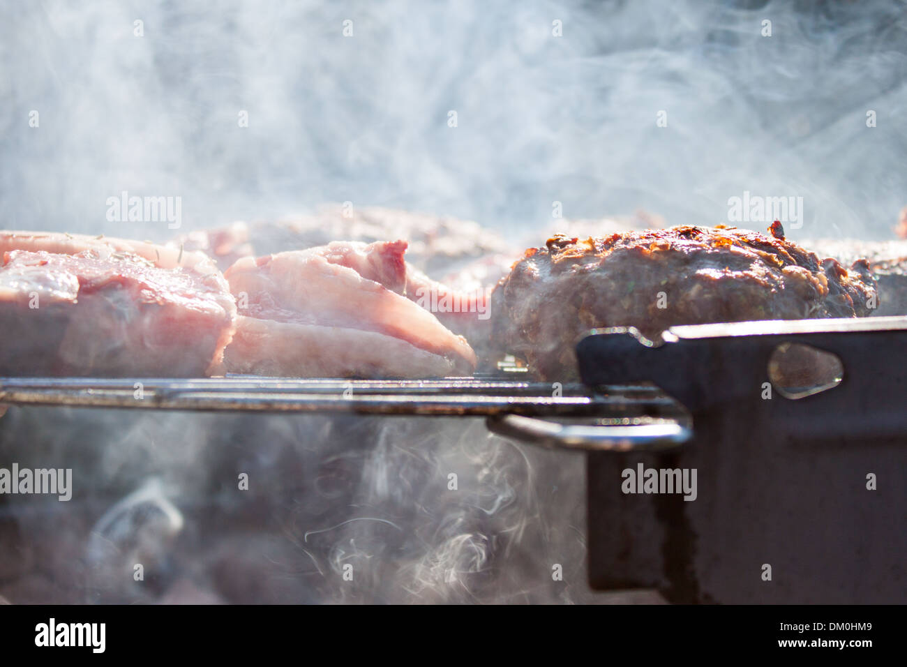 Cooking chops and burgers on a smoking summer barbeque Stock Photo - Alamy