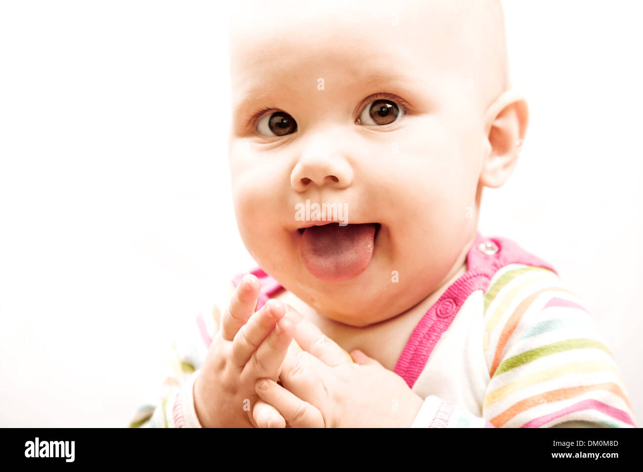 Funny little brown eyed Caucasian baby showing tongue Stock Photo - Alamy