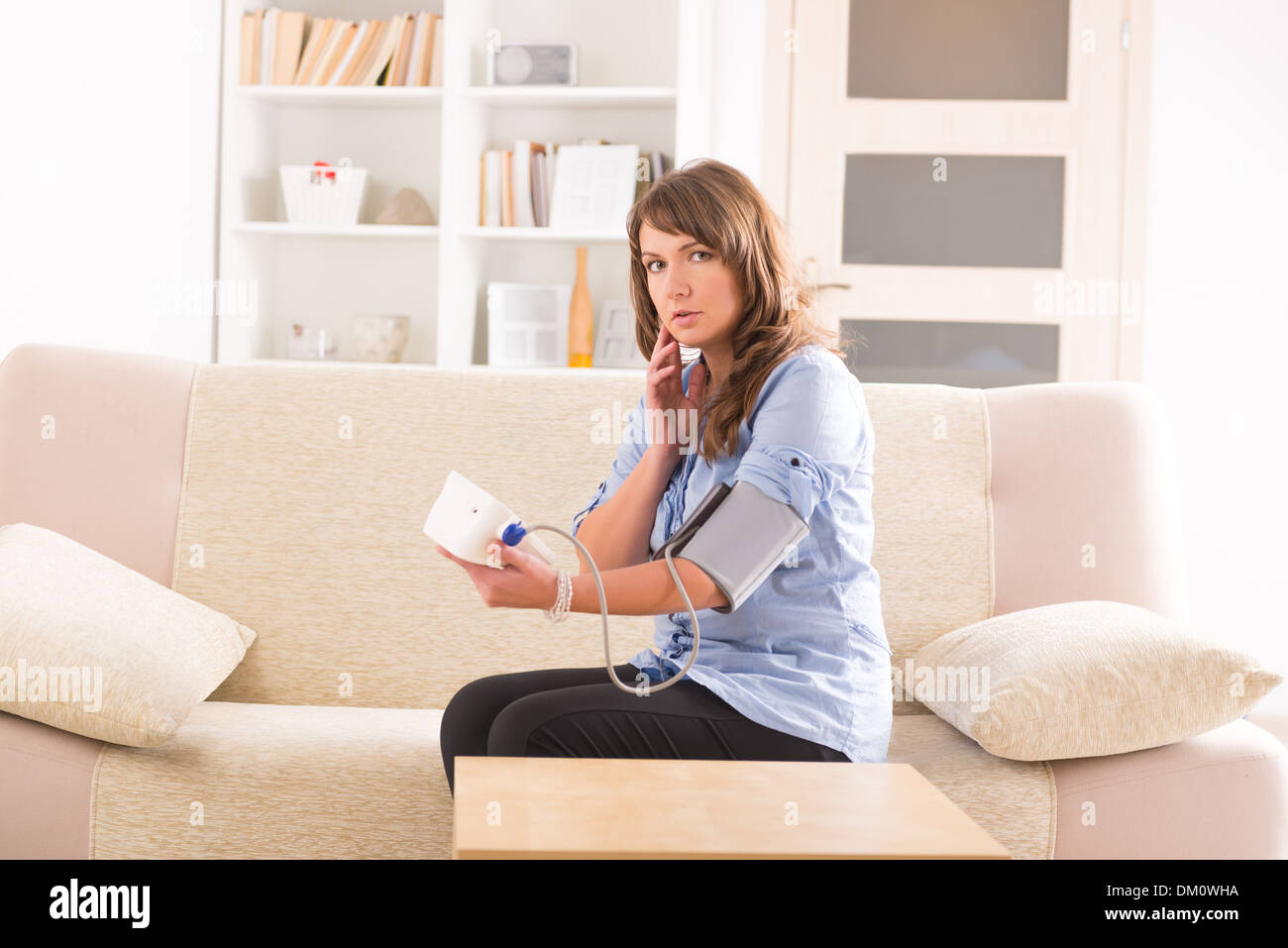 Beautiful woman checking her blood pressure at home Stock Photo - Alamy
