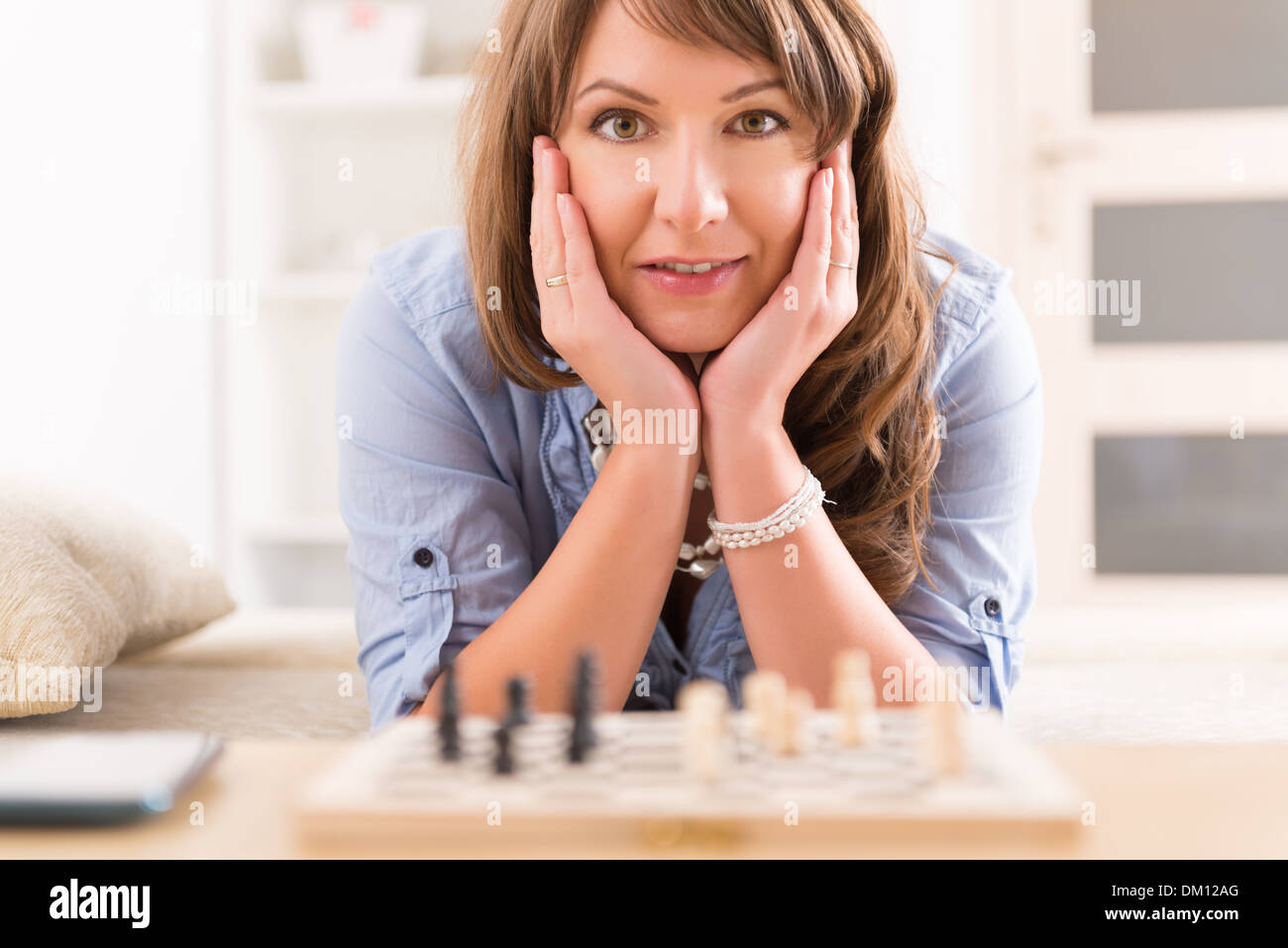 Beautiful woman playing chess on mini chessboard at home Stock Photo ...