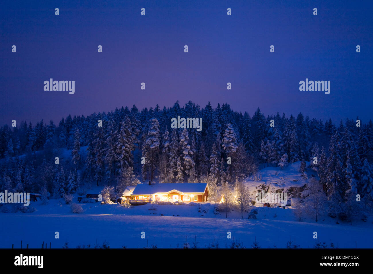 Cold Blue Evening light over snowy landscape with illuminated house ...