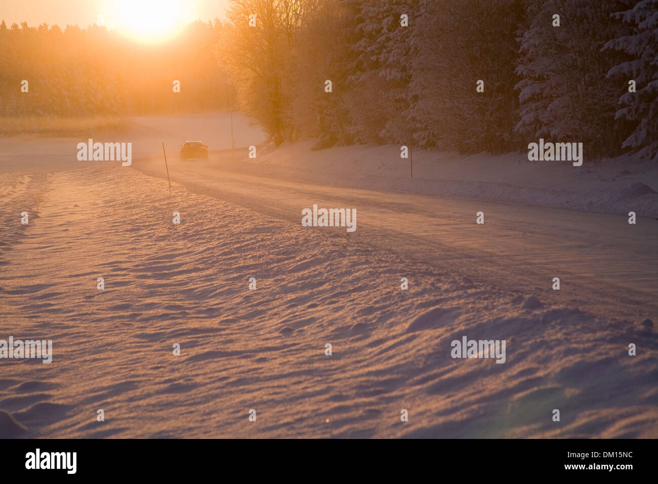 Snowy winter road with car in sunset Stock Photo - Alamy