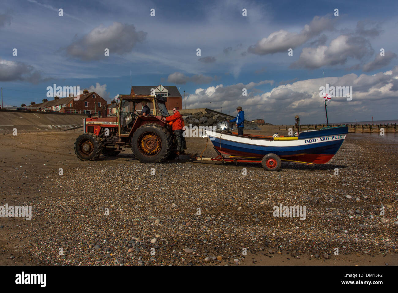 Tractor unit pulling small fishing boat up the beach to safety Stock ...