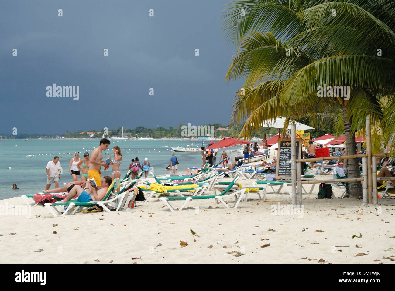 Sunning Tourists at 7-Mile Beach in Negril, Jamaica with Storm Clouds ...