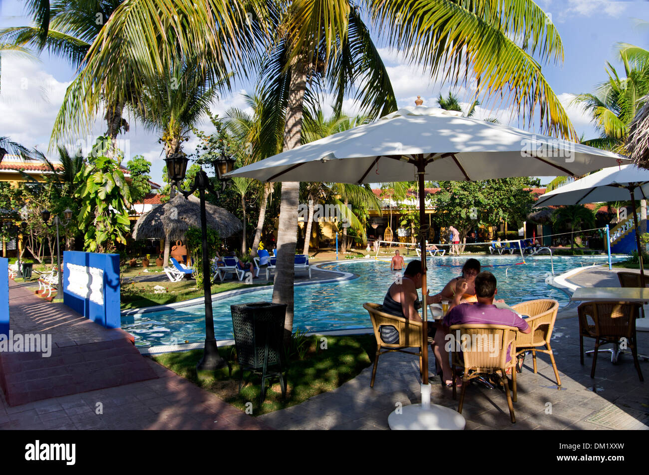 Three people sit at covered table by Las Brisas del Mar resortl pool ...