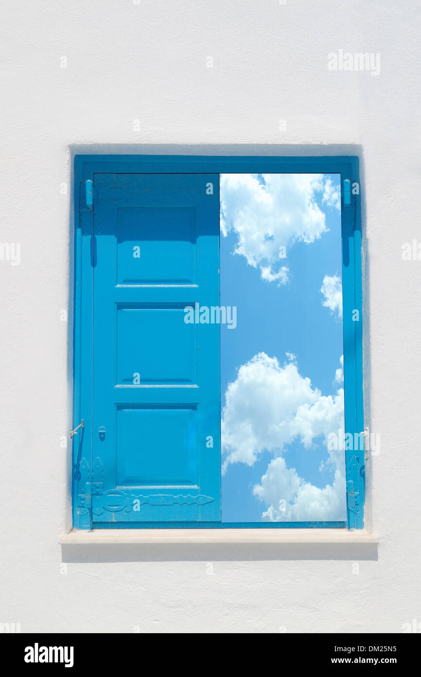 Traditional greek window against a white wall and the cloudy sky and ...