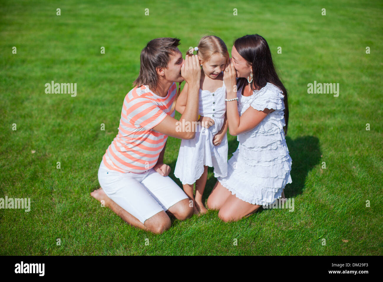 Young family of three sitting on the grass and have fun Stock Photo - Alamy