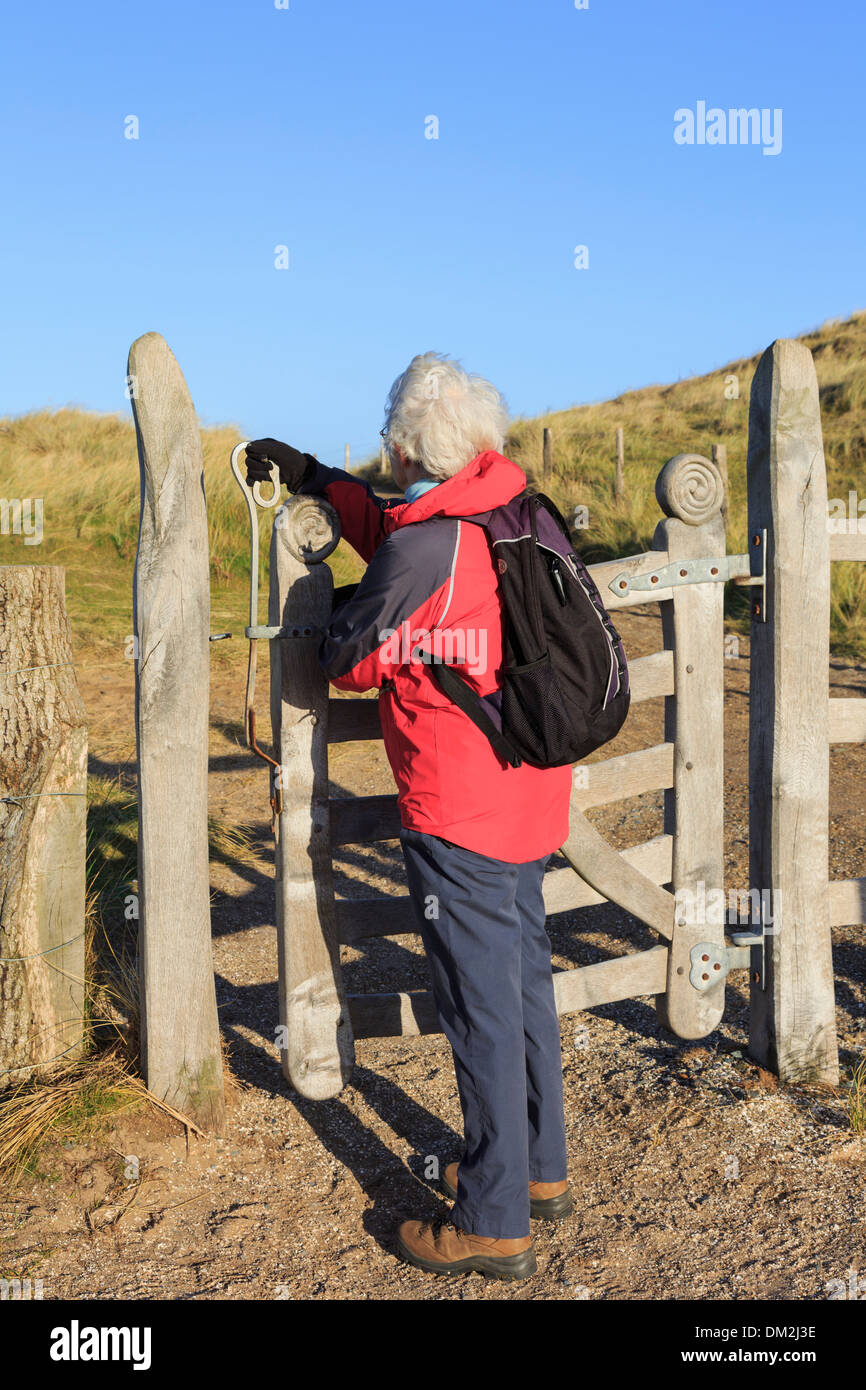 Senior woman walker opening a kissing gate on main path on Ynys ...