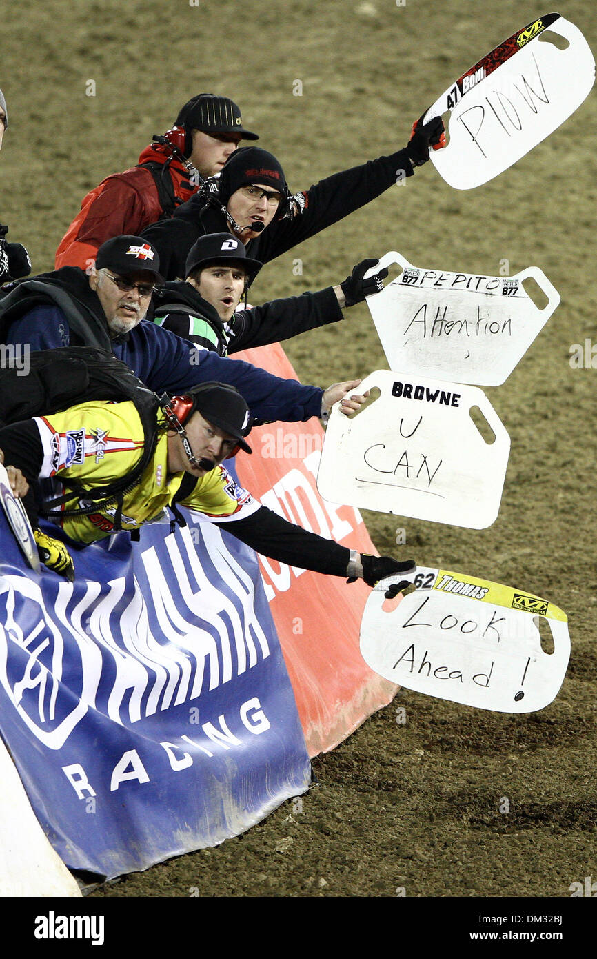 Pit crew members give directions to the riders as they come around turn ...