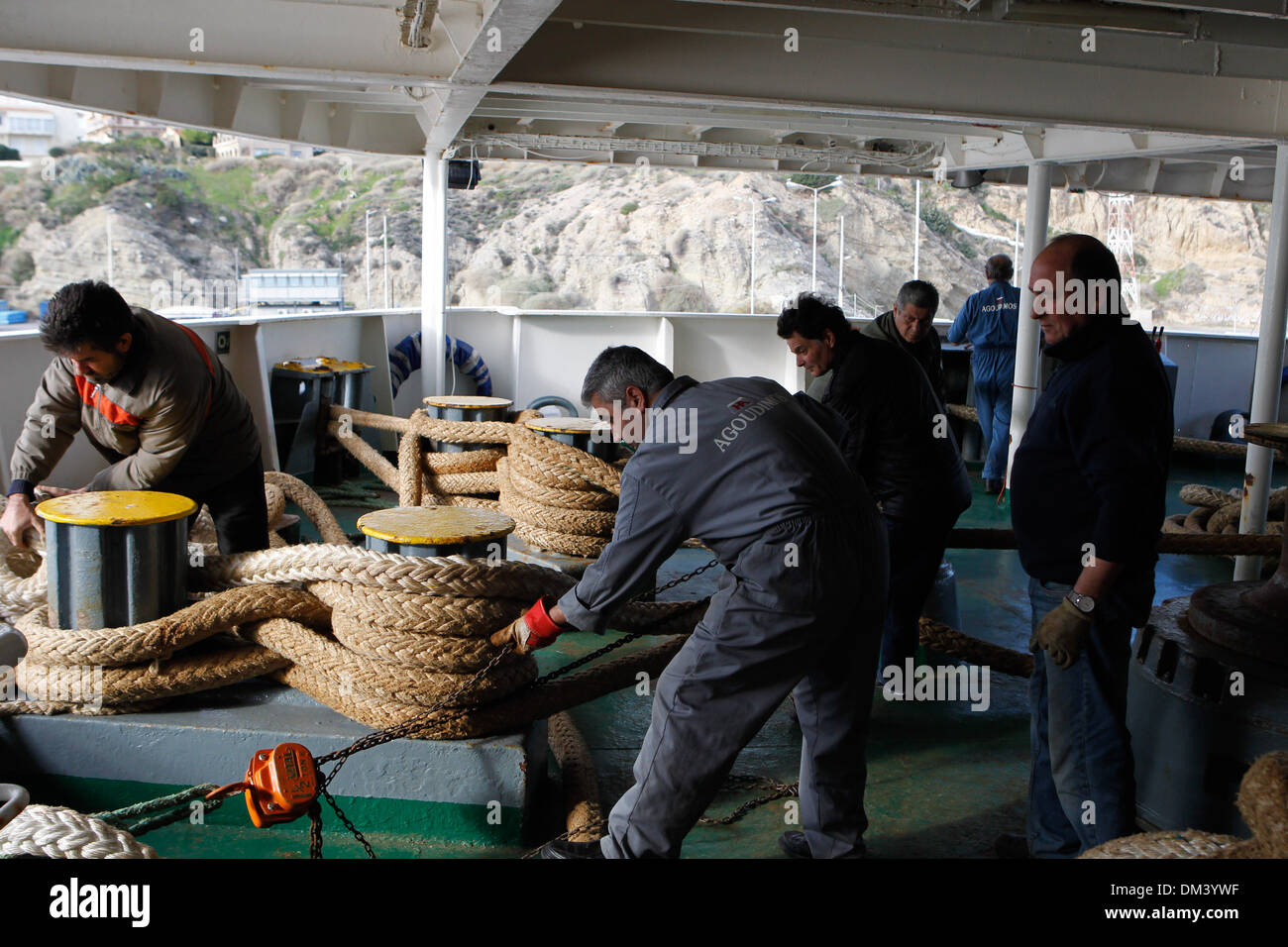 Ship crew guiding heavy duty mooring rope during docking procedure ...