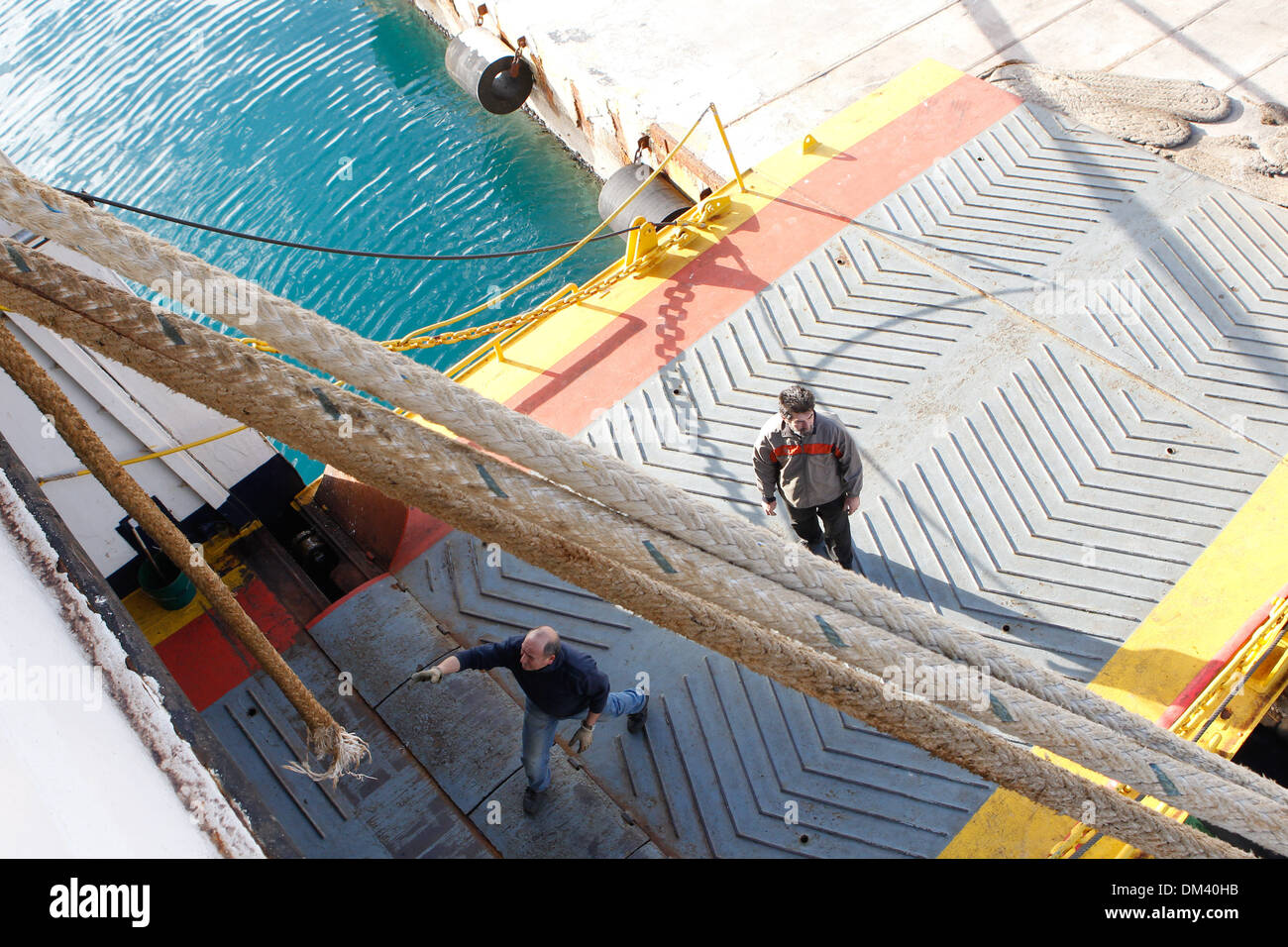 Ship crew guiding heavy duty mooring rope during docking procedure ...