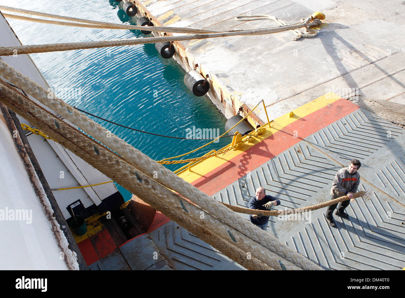 Ship crew guiding heavy duty mooring rope during docking procedure ...