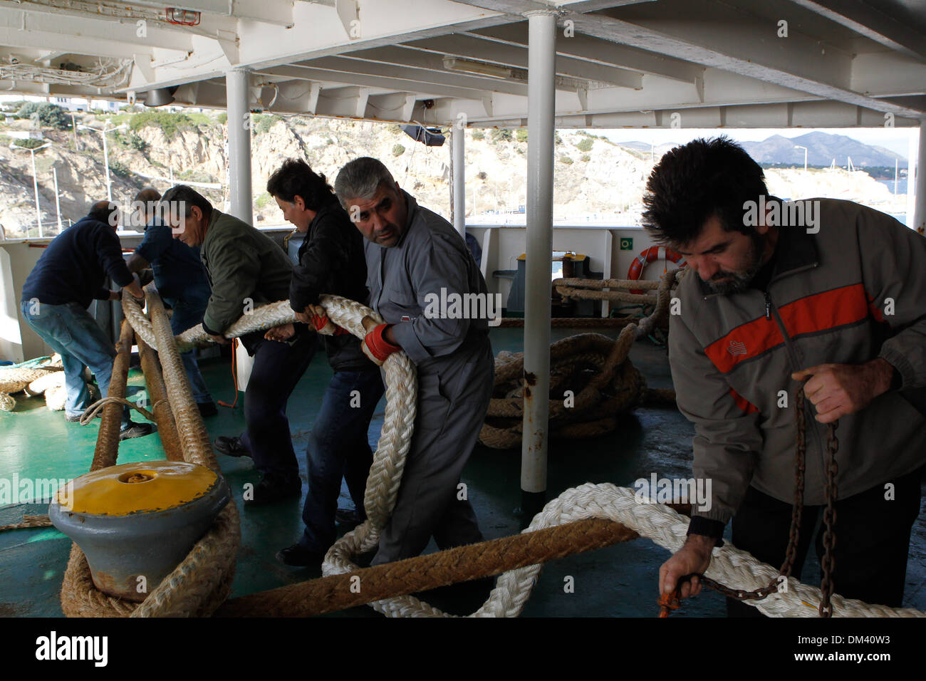 Ship crew guiding heavy duty mooring rope during docking procedure ...