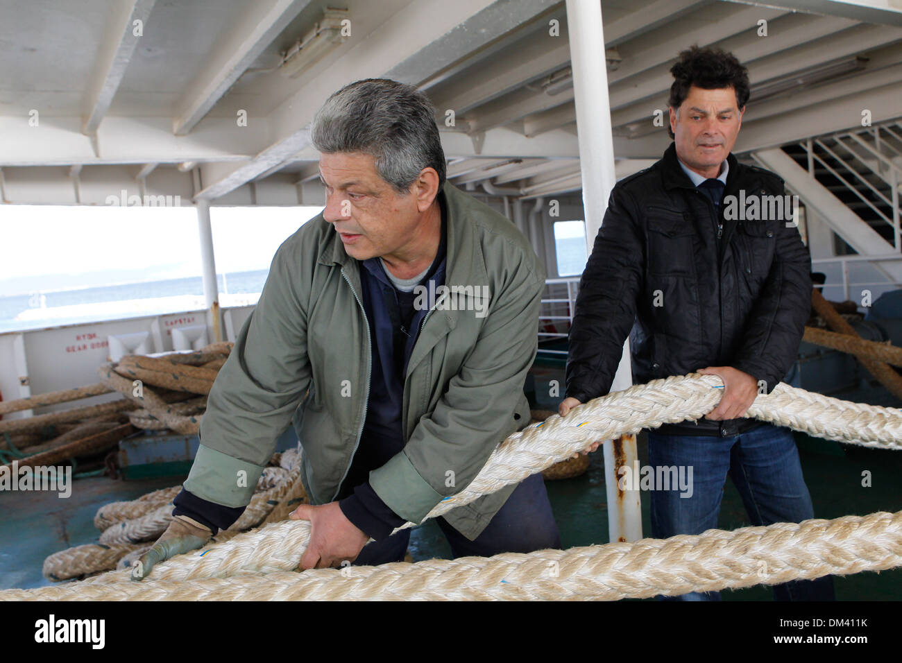 Ship crew guiding heavy duty mooring rope during docking procedure ...