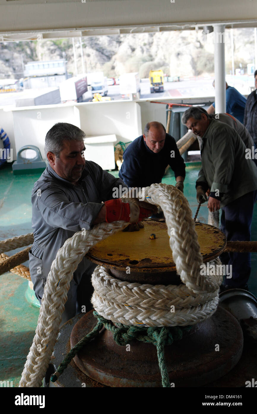 Ship crew guiding heavy duty mooring rope during docking procedure ...