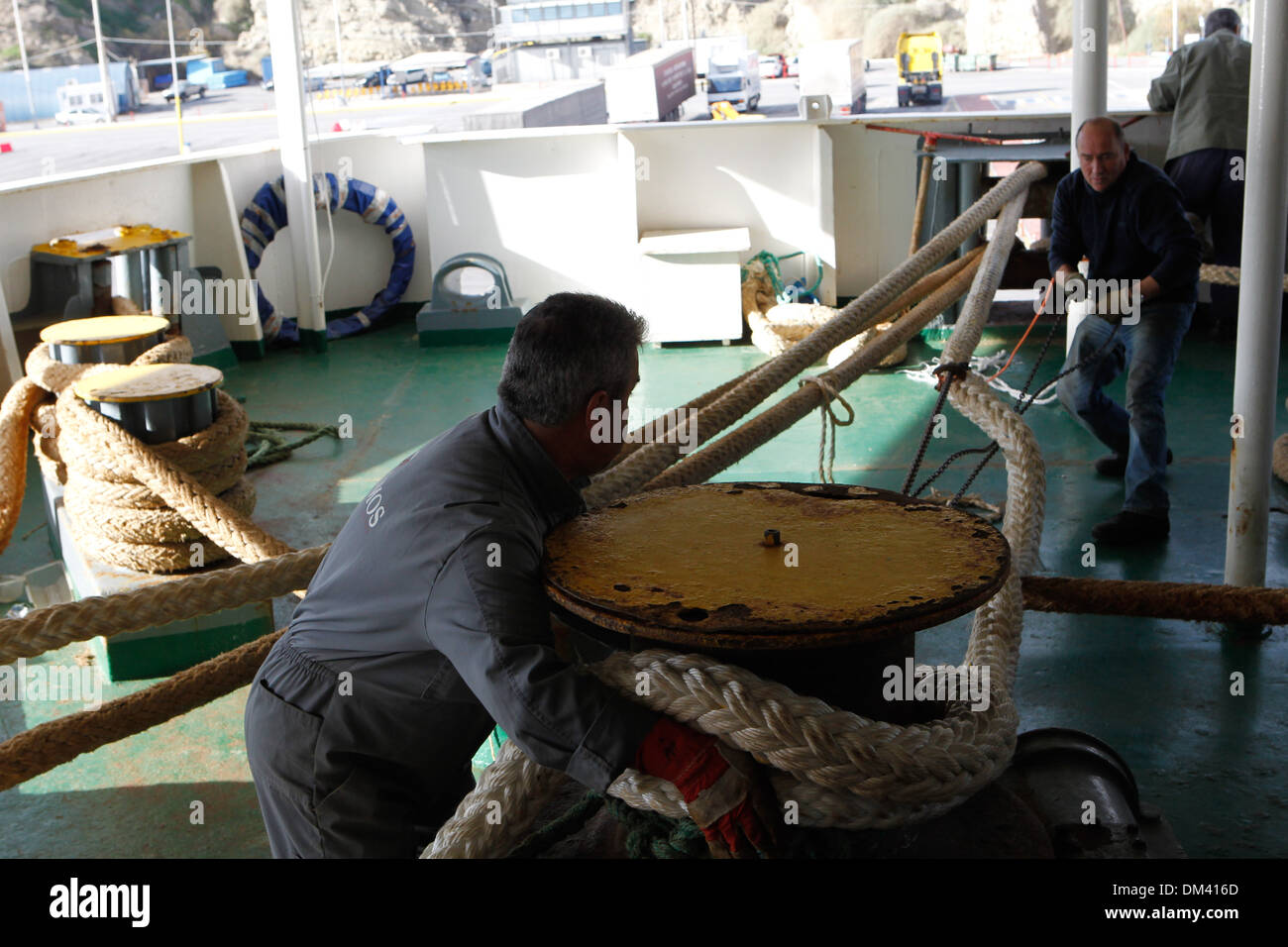 Ship crew guiding heavy duty mooring rope during docking procedure ...