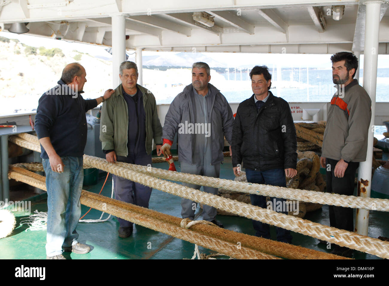 Ship crew guiding heavy duty mooring rope during docking procedure ...