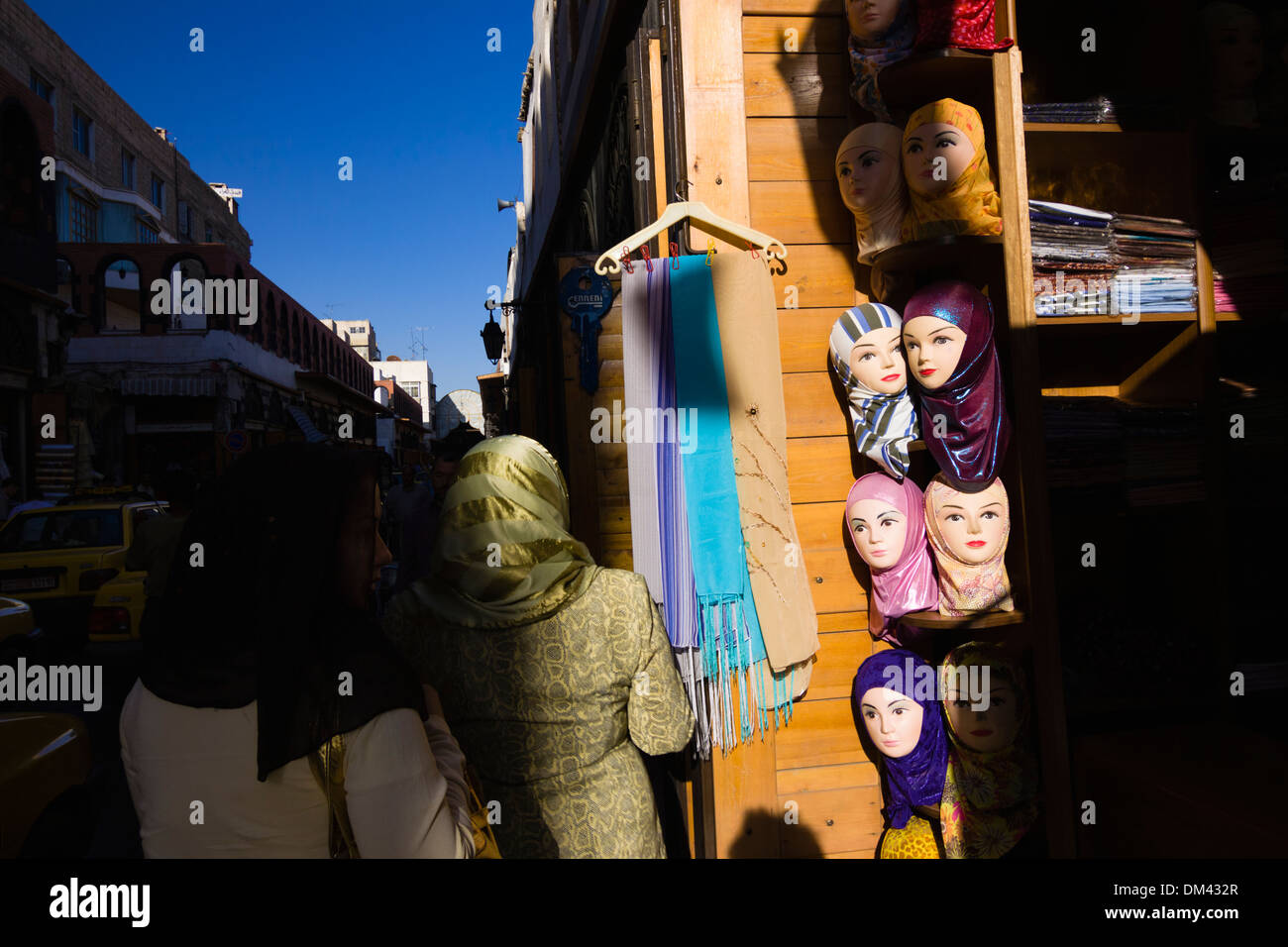 Arab women walk past a hijabs shop at the Via Recta street in Damascus ...